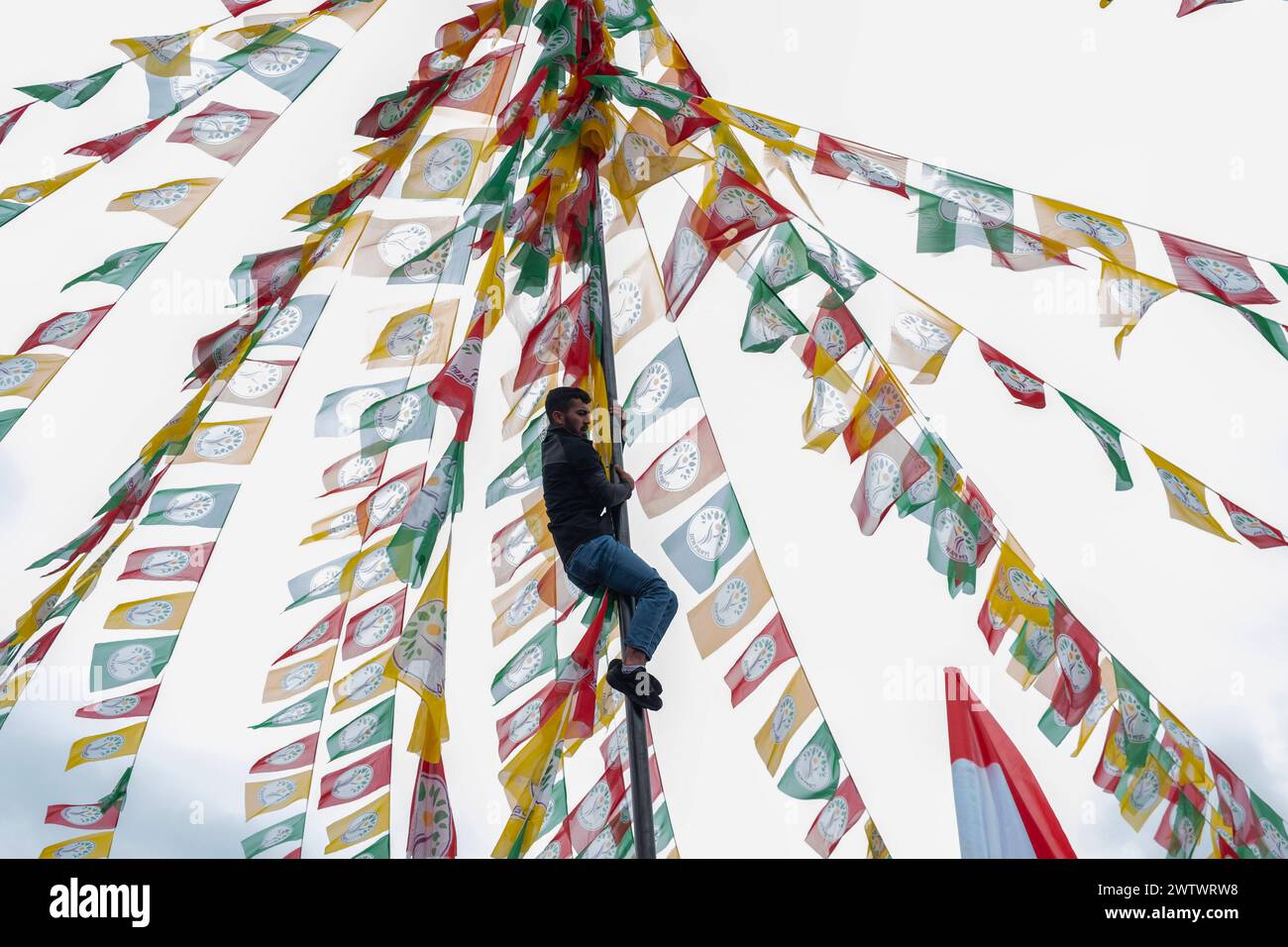 Batman, Turkey. 19th Mar, 2024. A young man climbs a pole with flags of ...