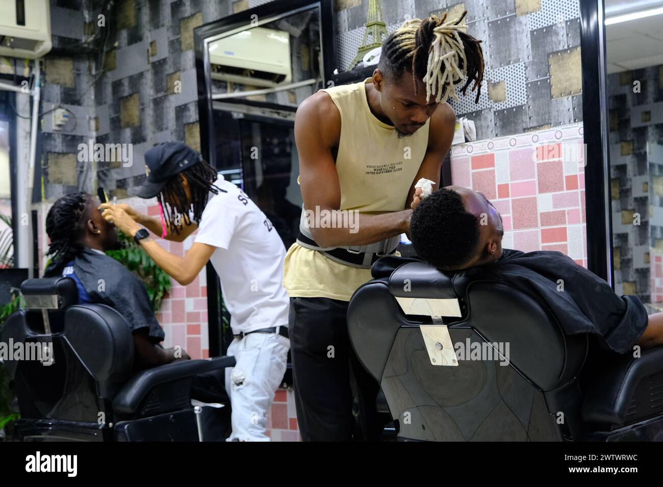 Barbers working with customers inside a barbershop in old town of Santo ...
