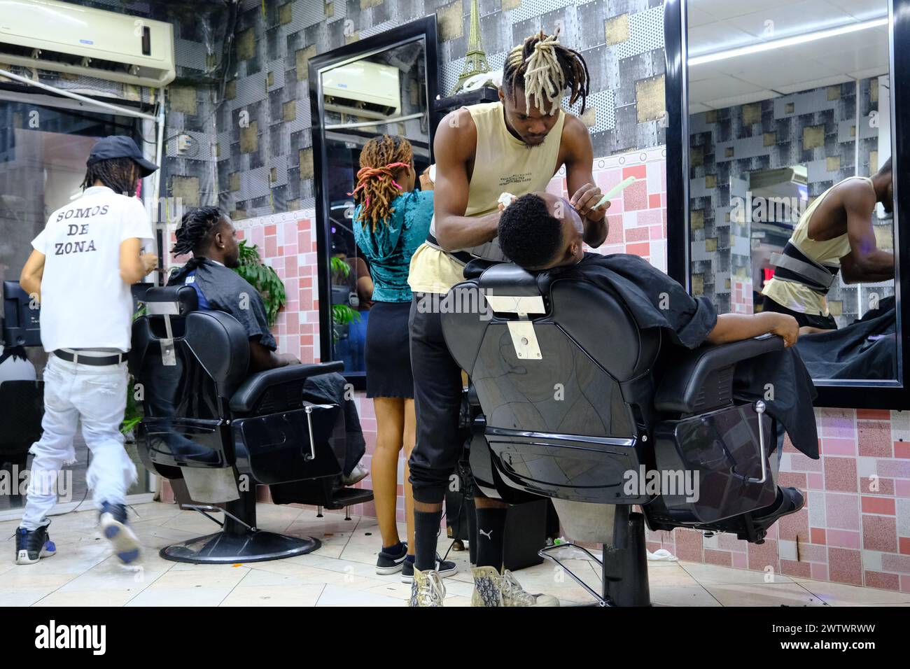 Barbers working with customers inside a barbershop in old town of Santo ...