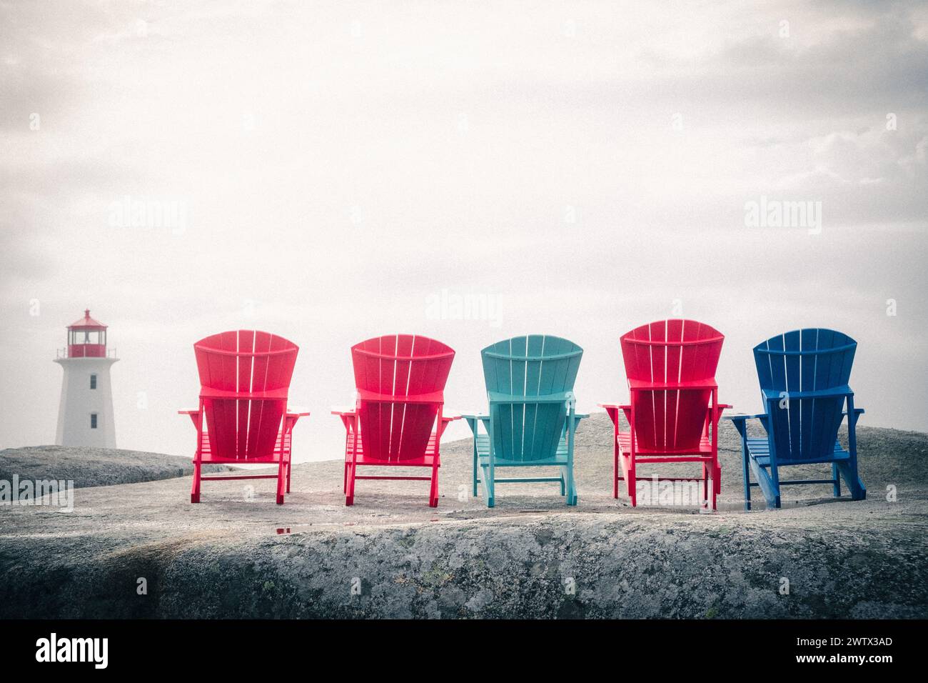 Row of red, blue and turquoise Adirondack chairs on the rocks in front ...