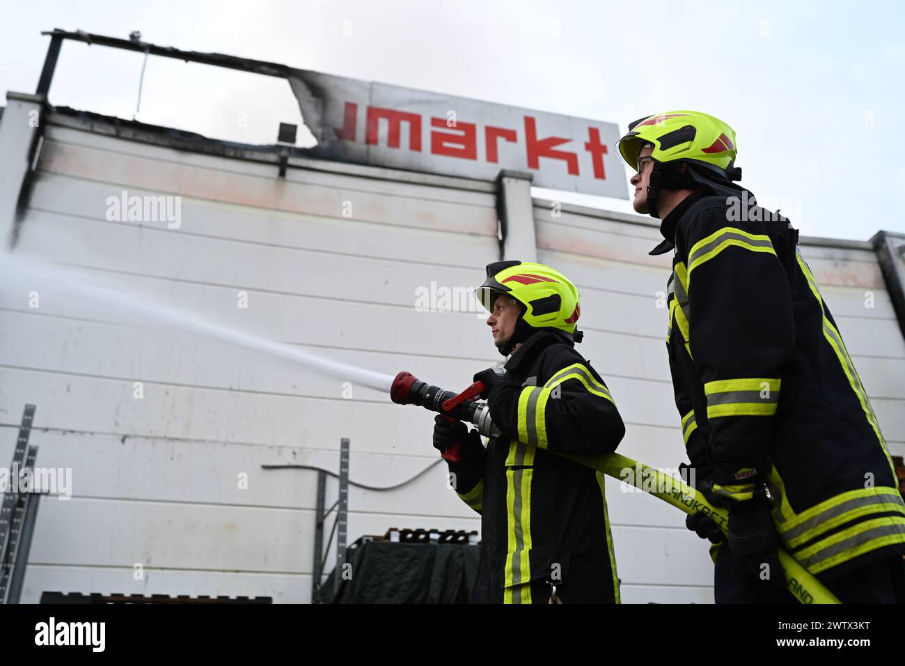 Varel, Germany. 20th Mar, 2024. Two firefighters cool the building from ...