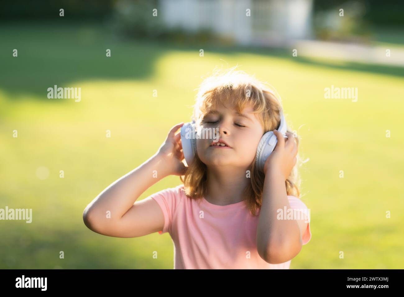 Emotional funny child in t-shirt in headphones in summer park. Children ...