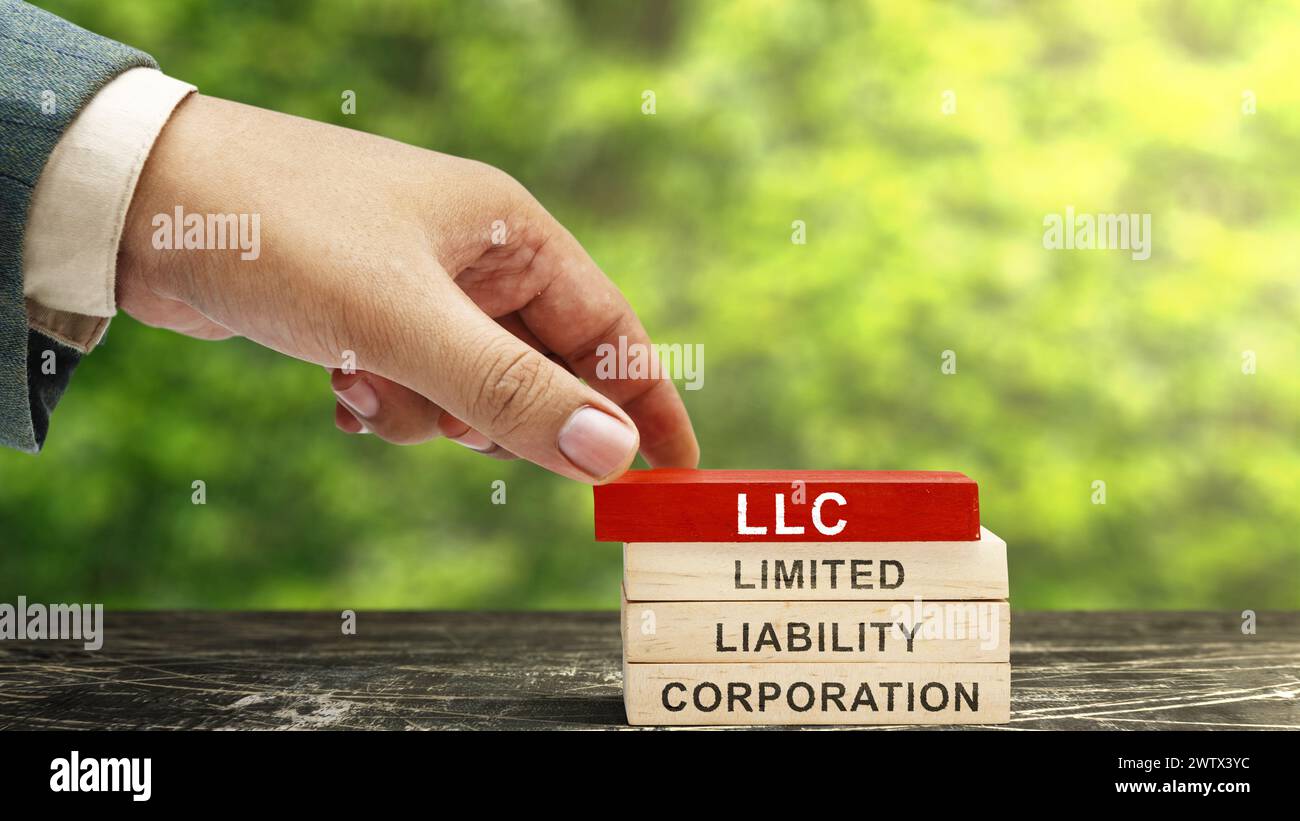 Business hand put a stack of wooden blocks with LLC text, the acronym ...