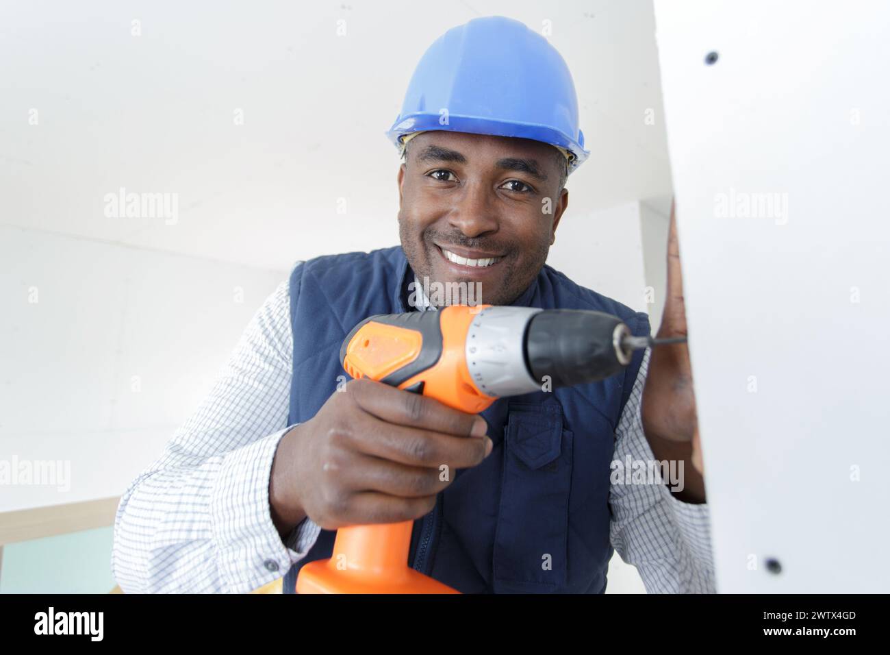 builder using cordless drill on plasterboard wall Stock Photo - Alamy
