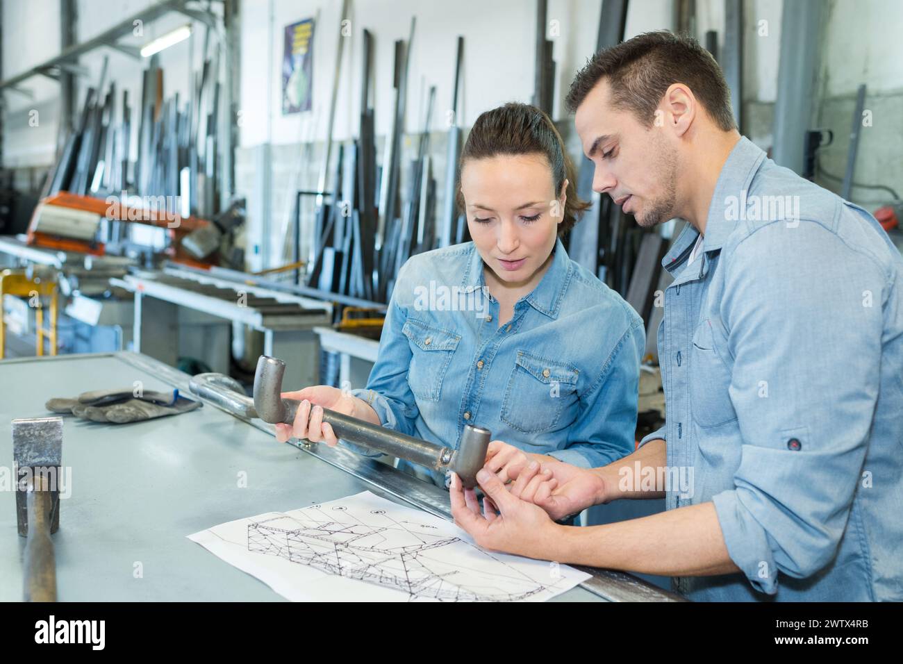 engineers holding metal part and looking at drawings Stock Photo - Alamy