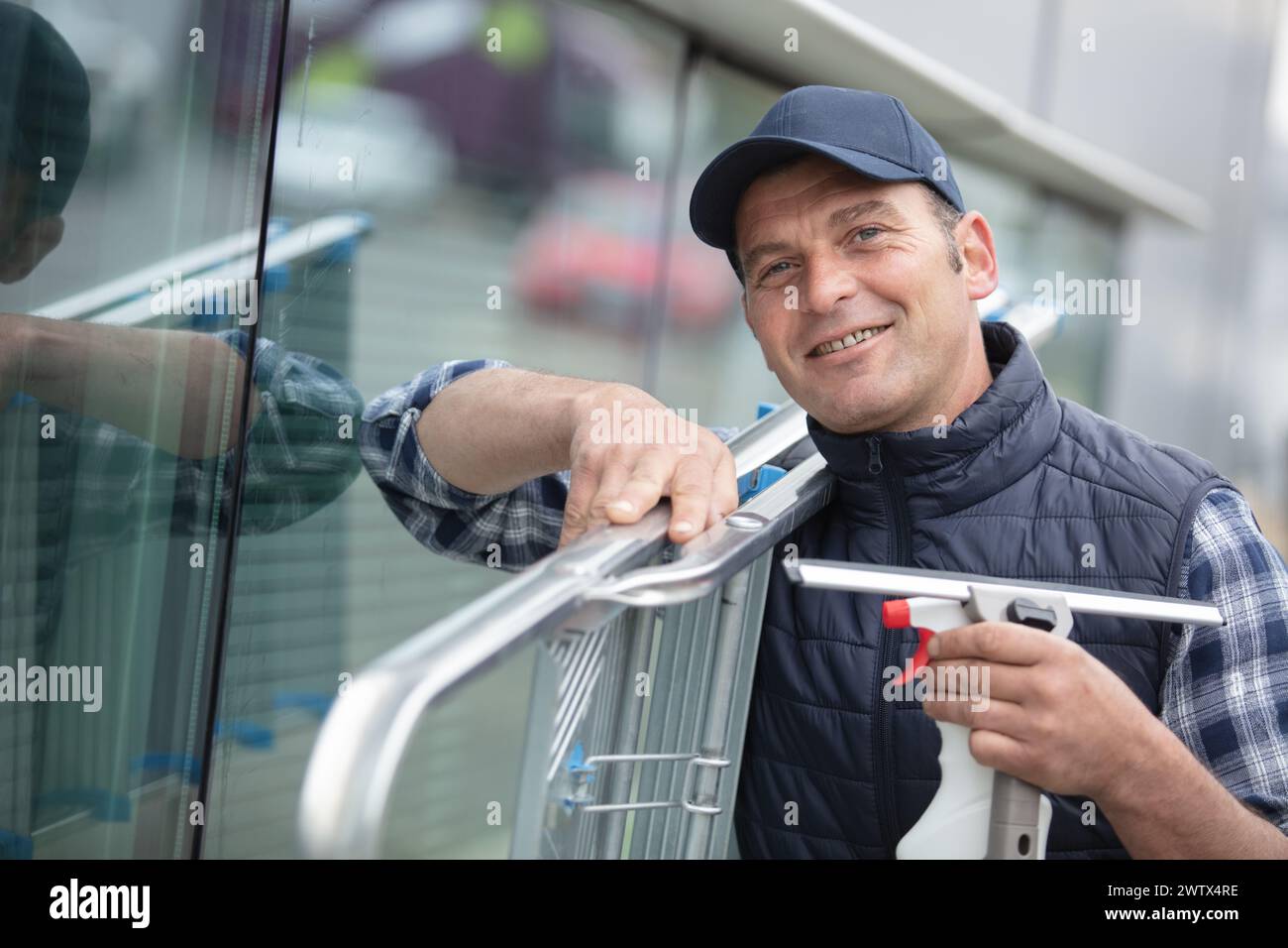 happy window cleaner holding a metal ladder Stock Photo - Alamy