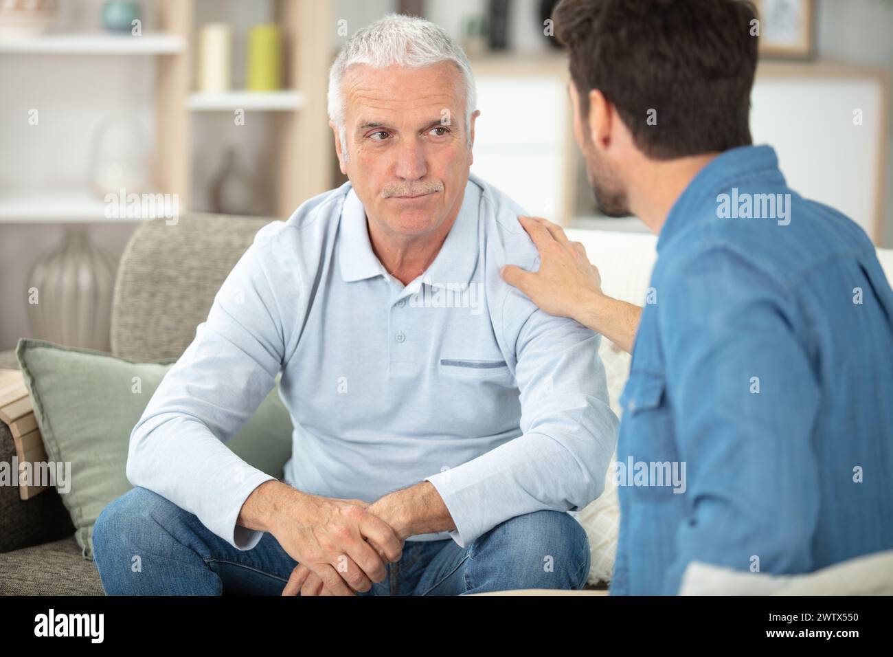 son comfort his aged father sitting on couch Stock Photo - Alamy