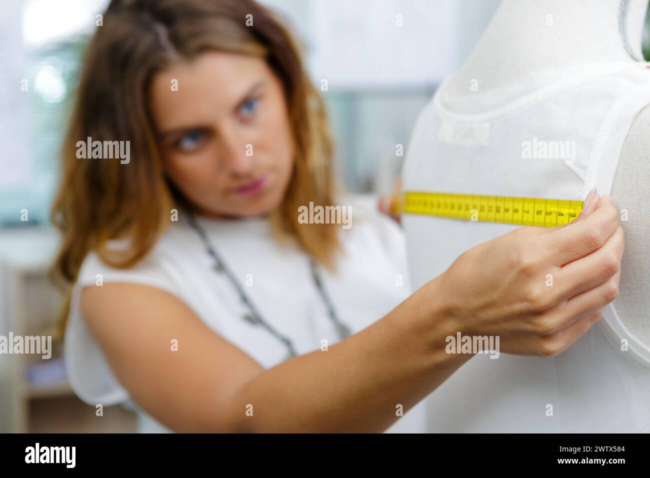 seamstress measuring back of manneuquin Stock Photo - Alamy
