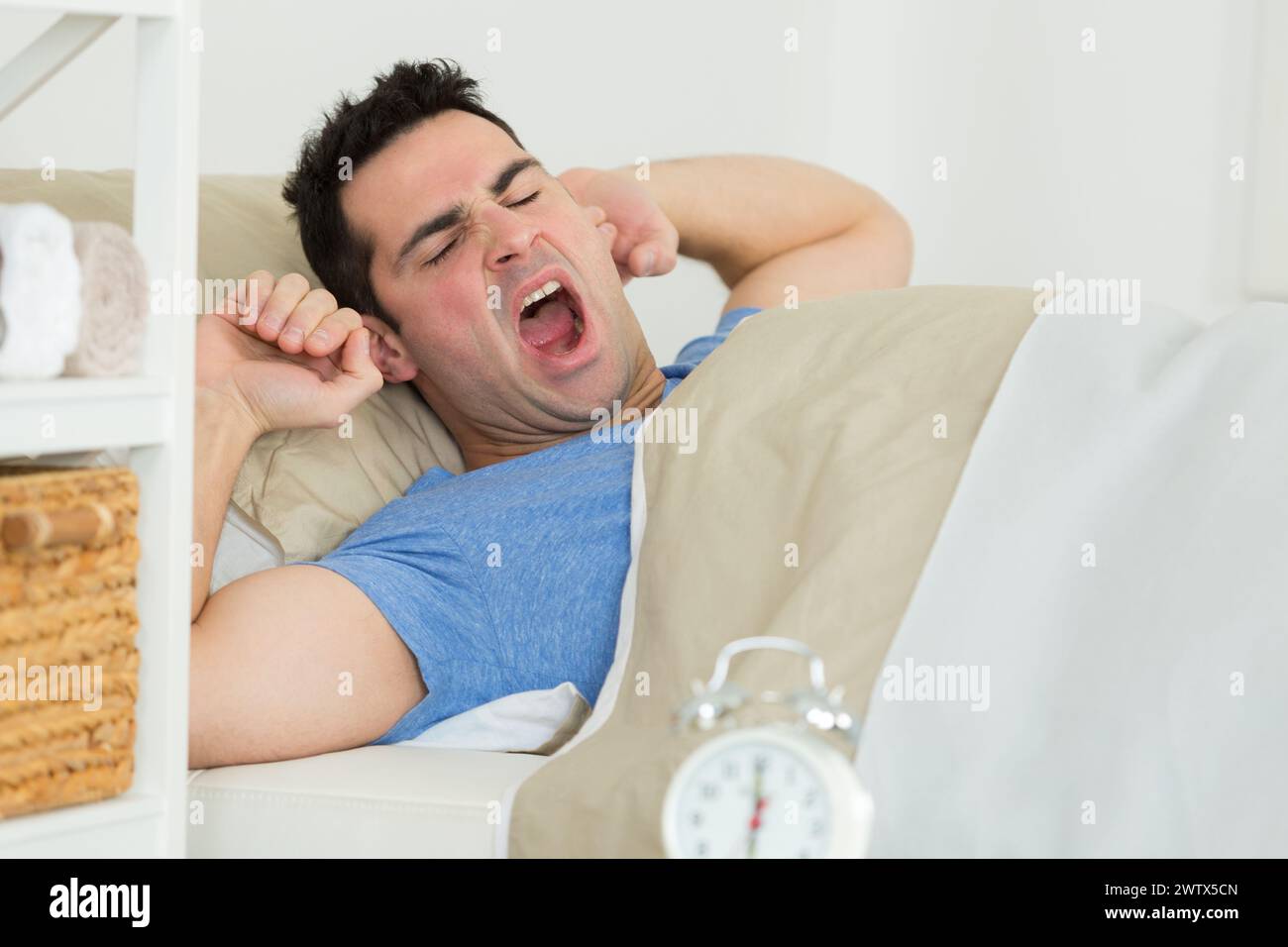 man stretching and yawning as he awakes in bed Stock Photo - Alamy