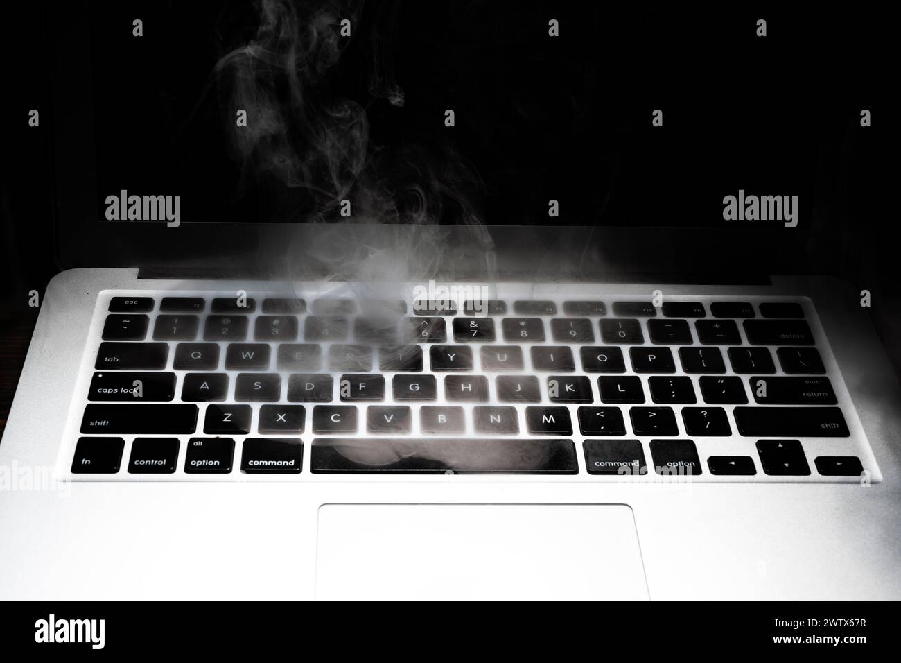 A broken laptop smoked on the wooden table. Breakdown gadget concept ...