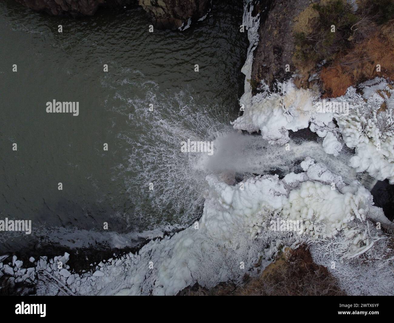 Ice flows from a dam into the water in a scenic winter setting Stock ...