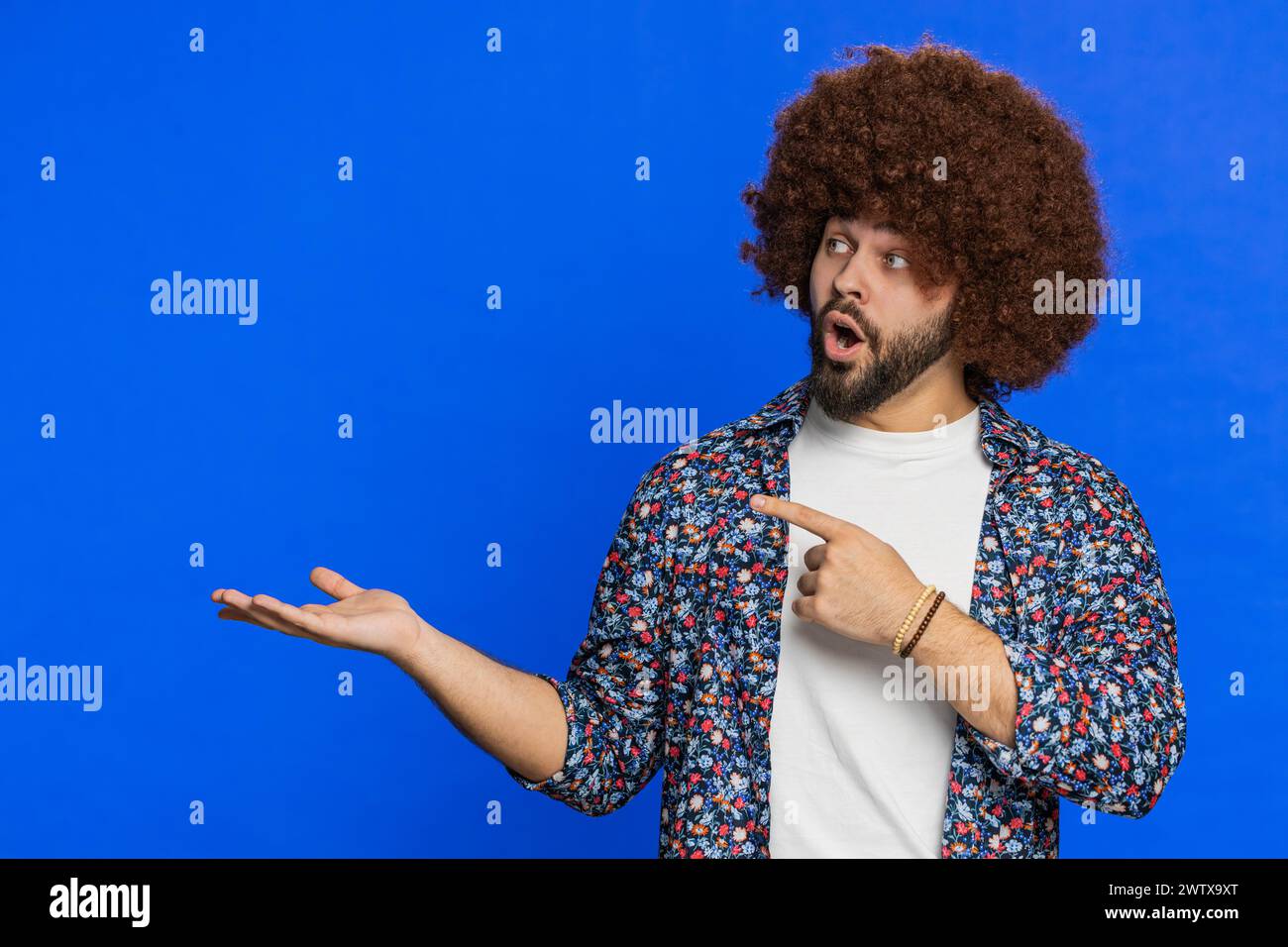 Happy amazed man with Afro hairstyle wig showing pointing left empty ...