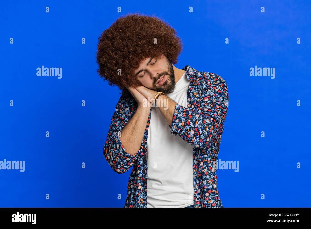 Tired exhausted young adult sleepy man with Afro hairstyle wig ...