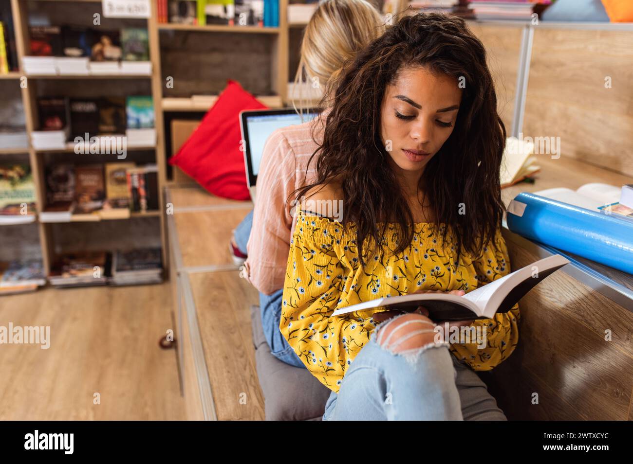 Young female African American student study in the library reading book ...