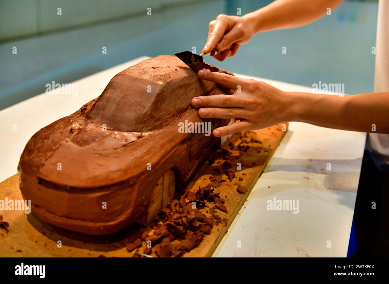 Designers work on the car's sculpture using carving tools. Adjust the ...