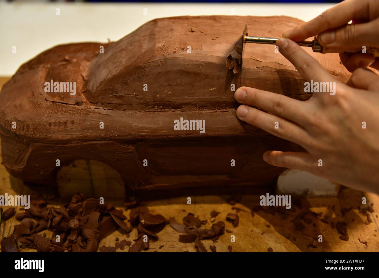 Designers work on the car's sculpture using carving tools. Adjust the ...