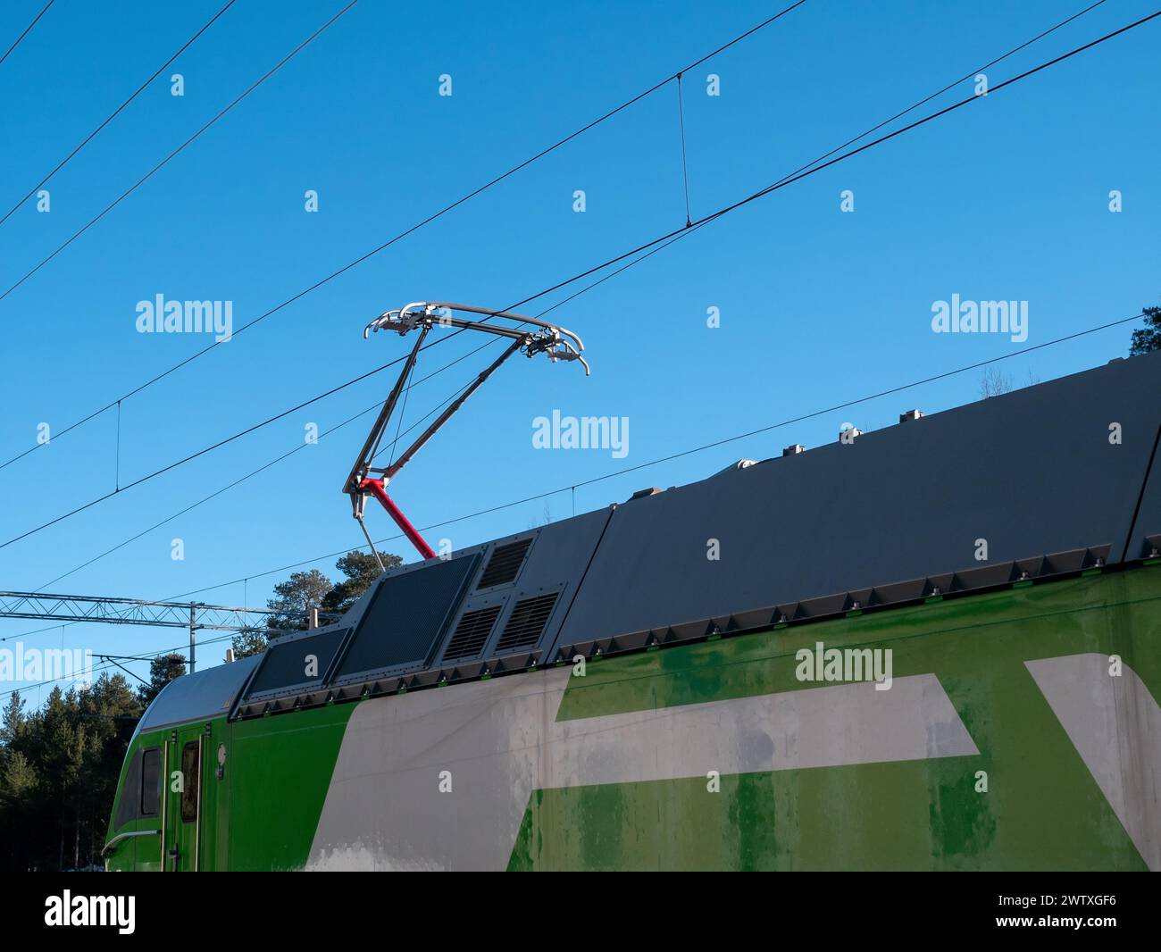 pantograph mounted on the roof of an electric train against blue sky ...