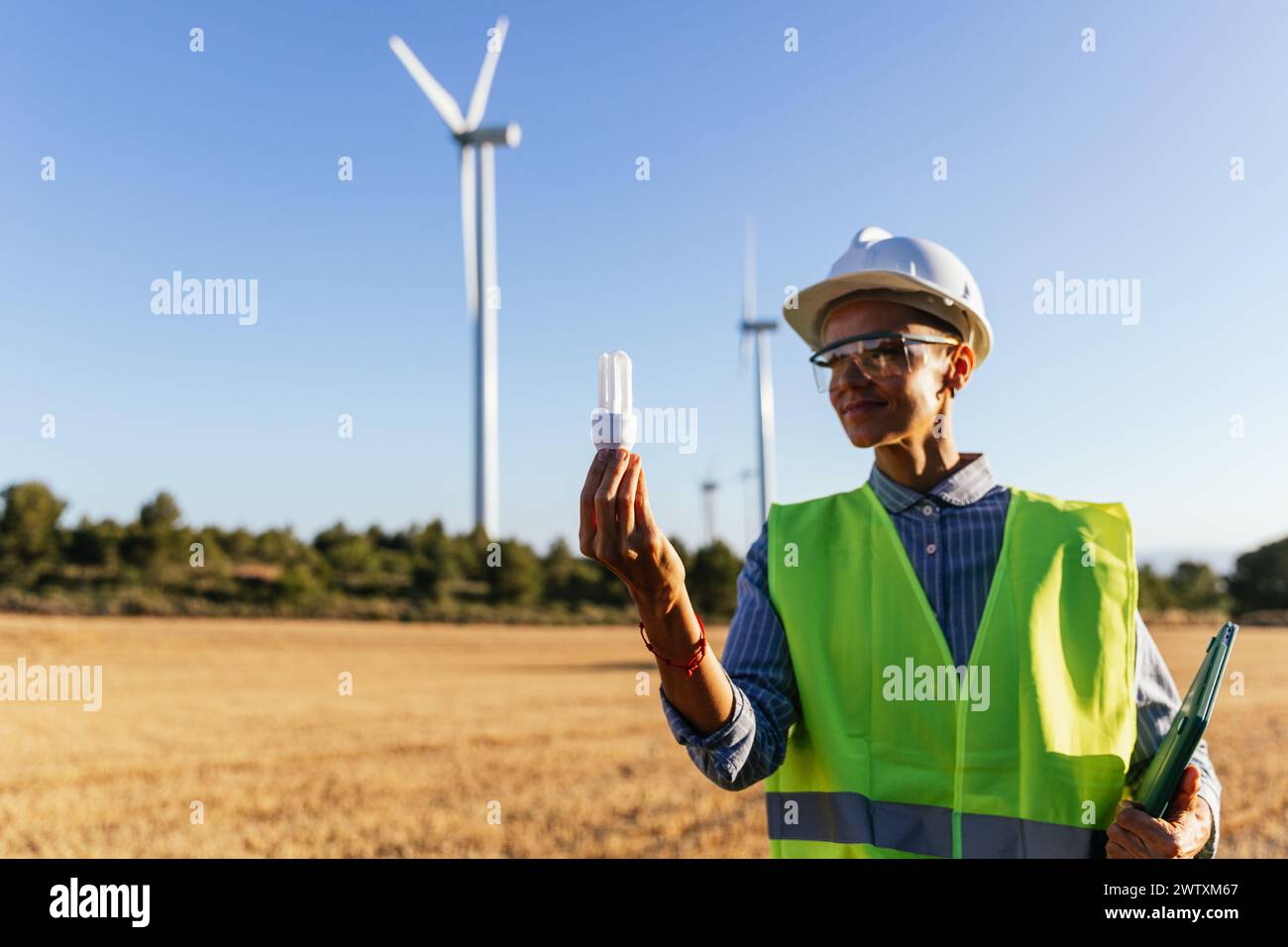 Electrical engineer holding energy saving light bulb on unfocused ...