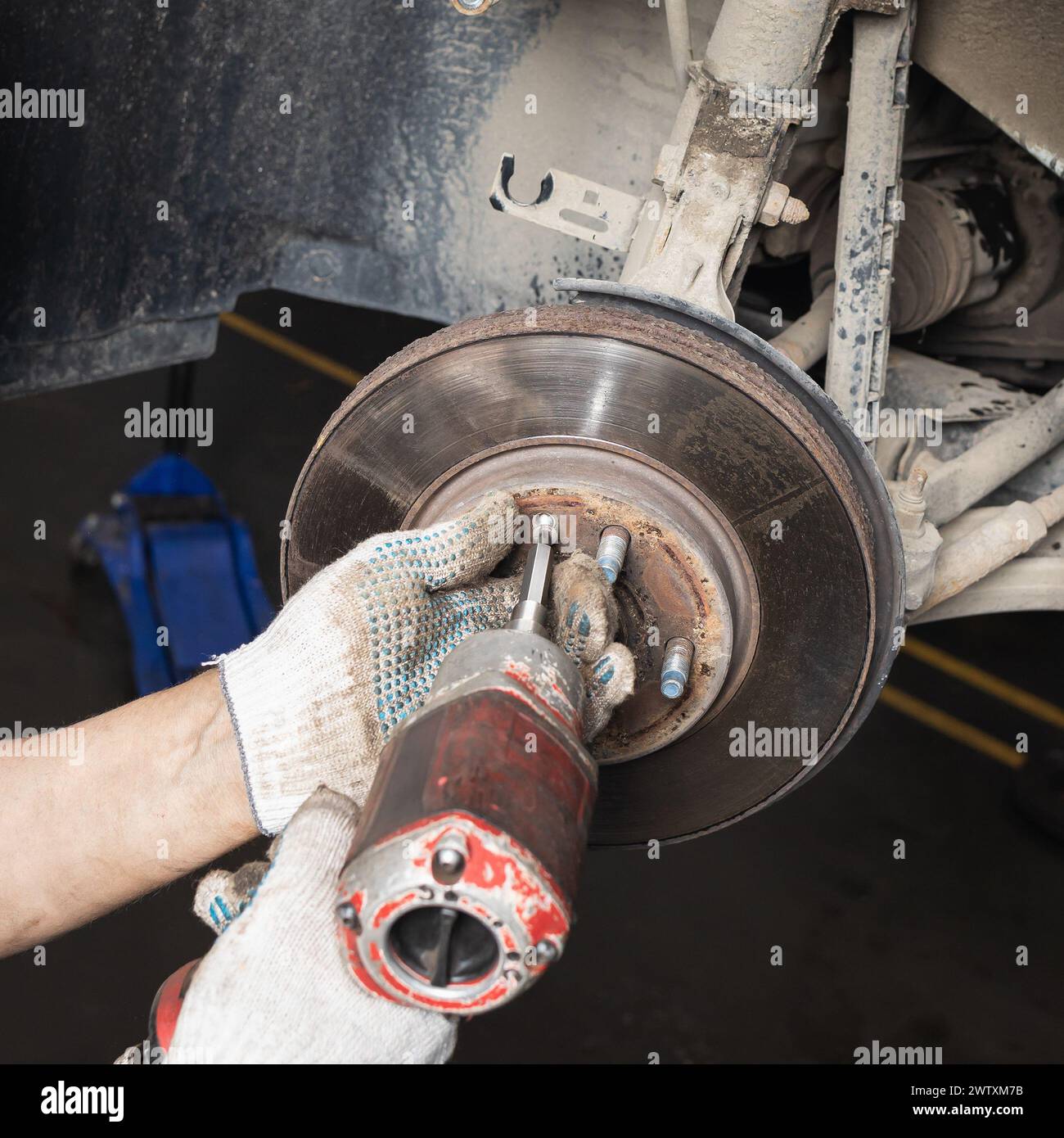 An auto mechanic uses a pneumatic screwdriver to unscrew the bolts on ...