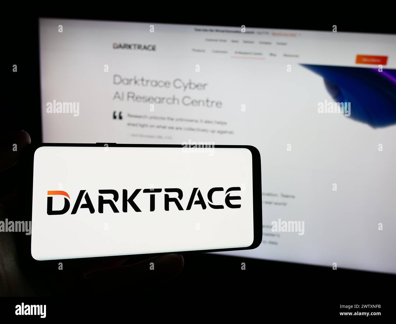 Person holding mobile phone with logo of British cyber security company ...