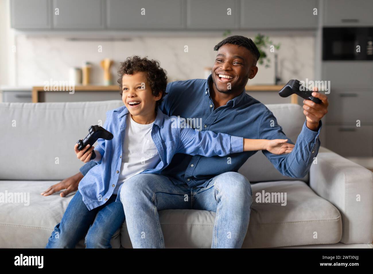 Father and son playing video games and laughing Stock Photo - Alamy