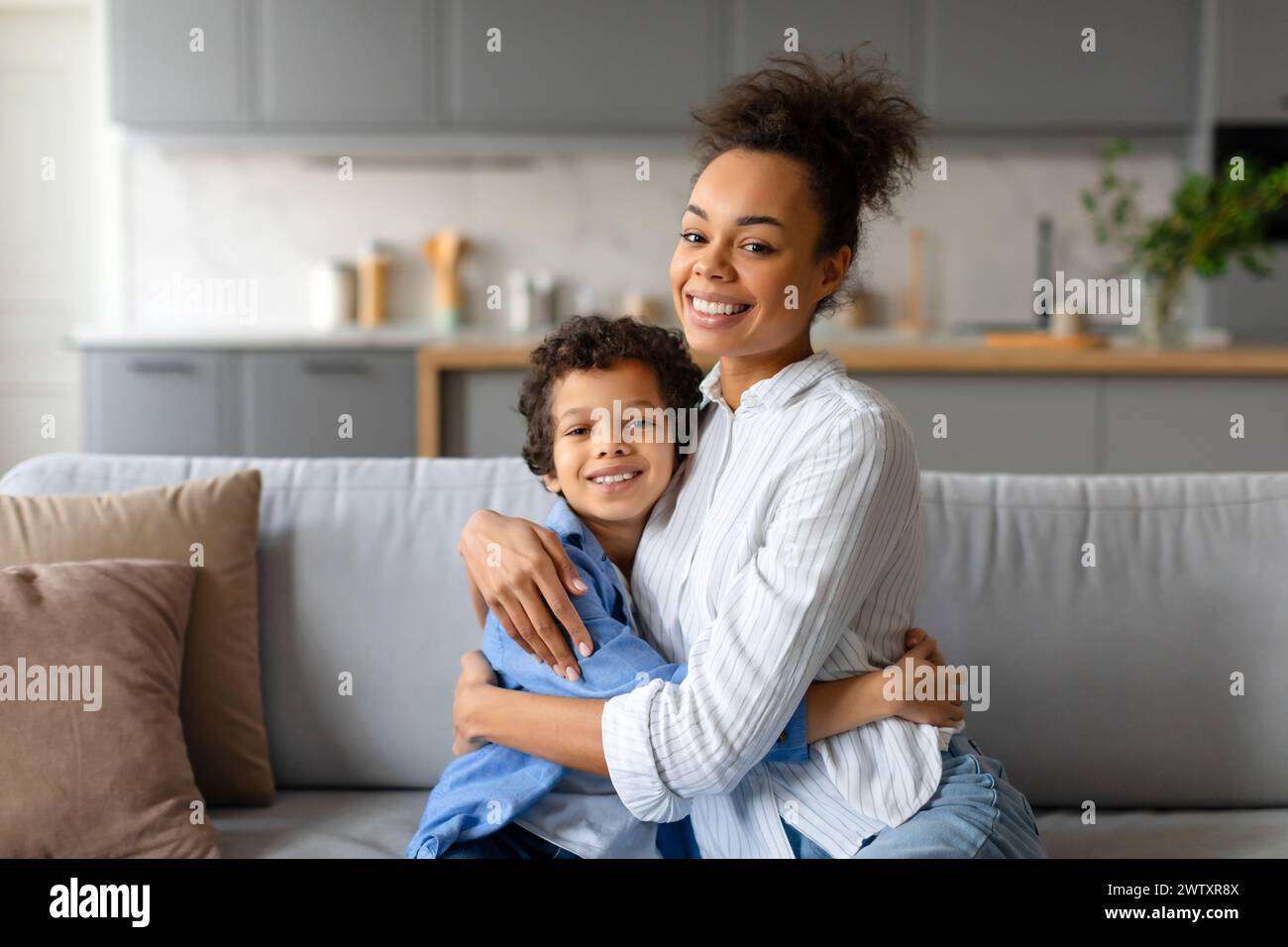Joyful mother and son sitting on couch Stock Photo - Alamy