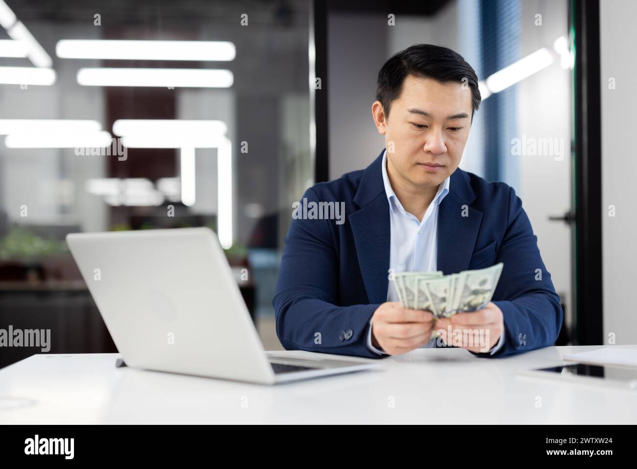 Focused businessman counting money while working at a laptop in a ...