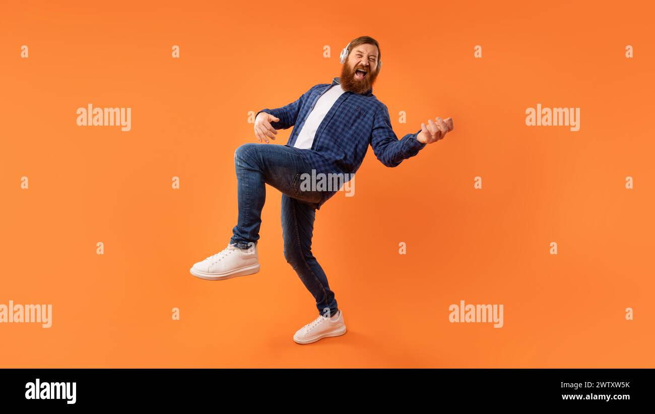 Energetic guy enjoying music through headphones playing invisible ...