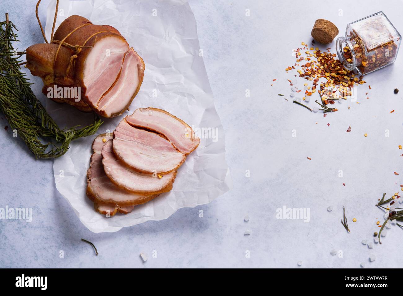 smoked spicy pork roll on white parchment cut into slices surrounded by ...