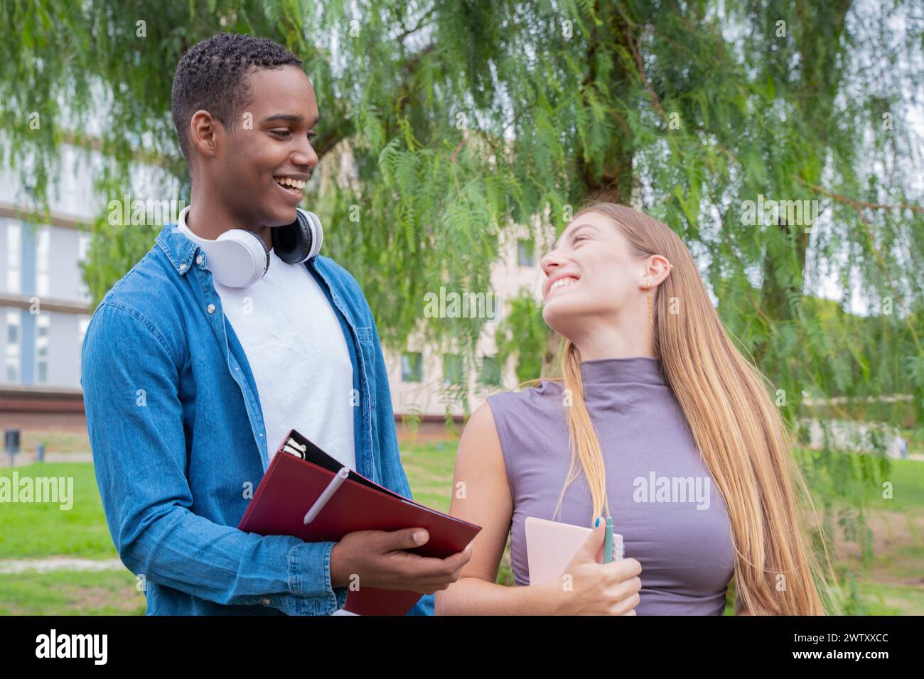 Smiling college friends looking at notes, talking and laughing on ...