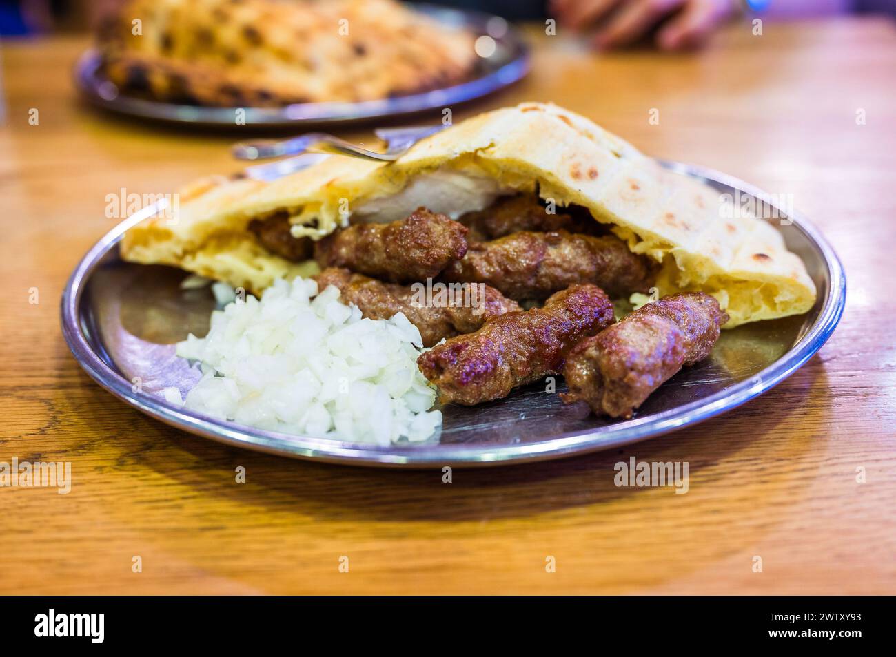 Traditional bosnian barbecue dish cevapi served with somun and chopped ...