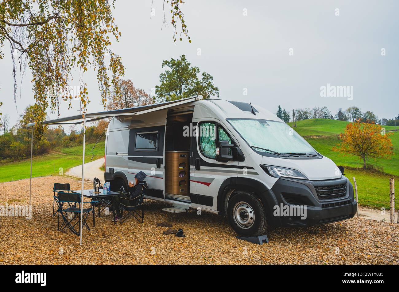 Campervan or motorhome parked in the countryside nature. Woman is ...