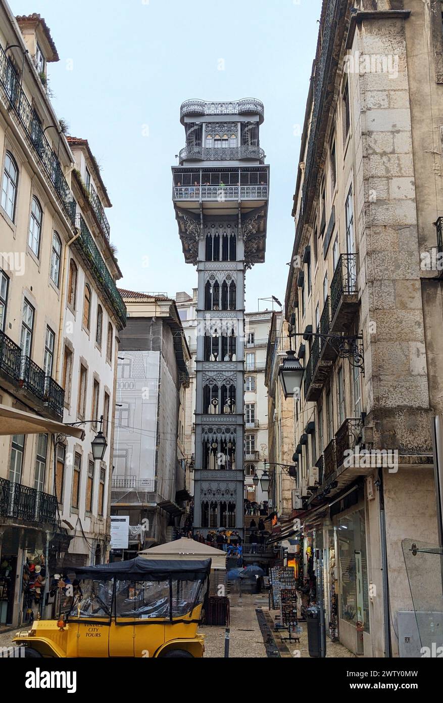 A yellow bus parked in front of high-rise buildings with balconies ...