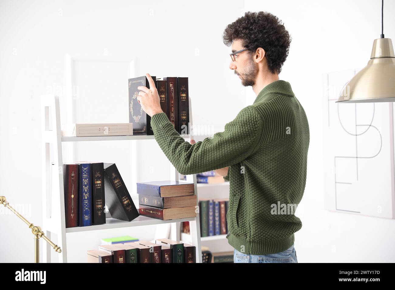 Male student taking book from shelf in library Stock Photo - Alamy