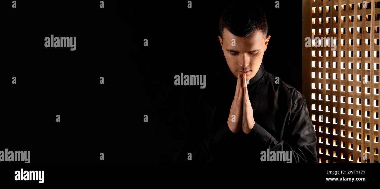Young priest praying in confession booth. Banner for design Stock Photo ...