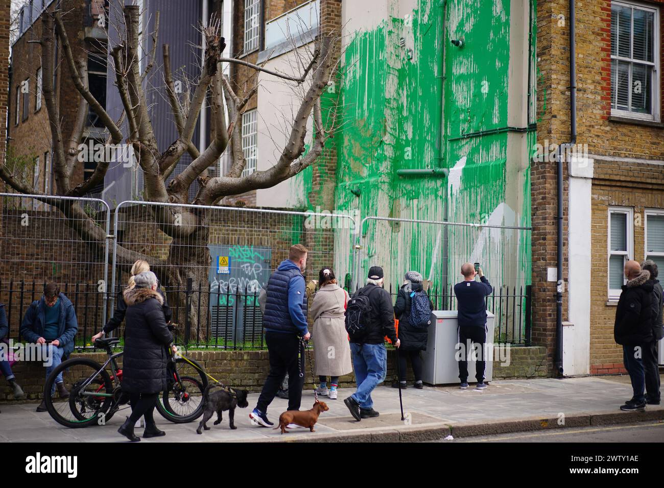 People looking at Banksy artwork which has been defaced with white ...