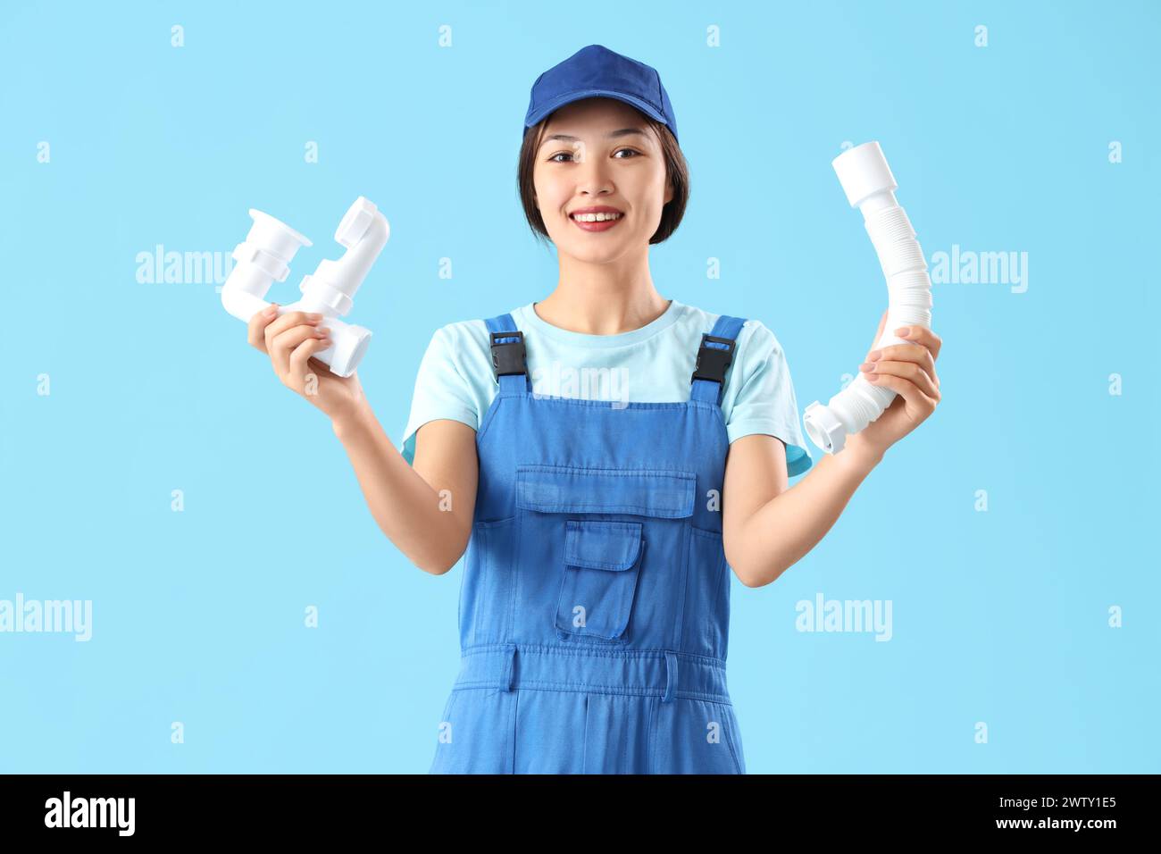 Female Asian plumber with pipes on blue background Stock Photo - Alamy