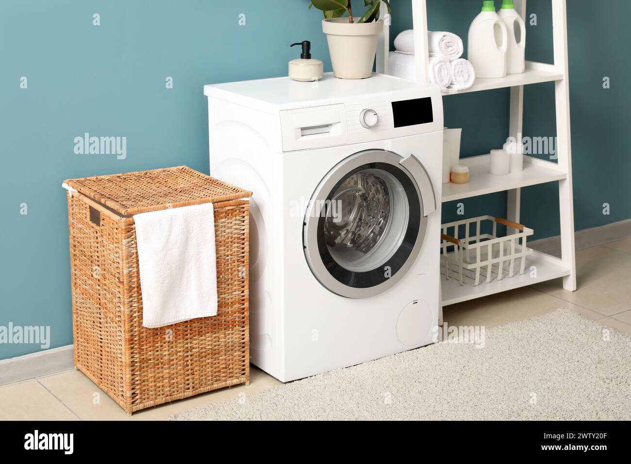 Interior of room with laundry basket, washing machine and shelf unit ...