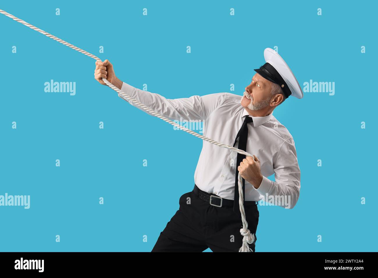 Mature sailor pulling rope on blue background Stock Photo - Alamy