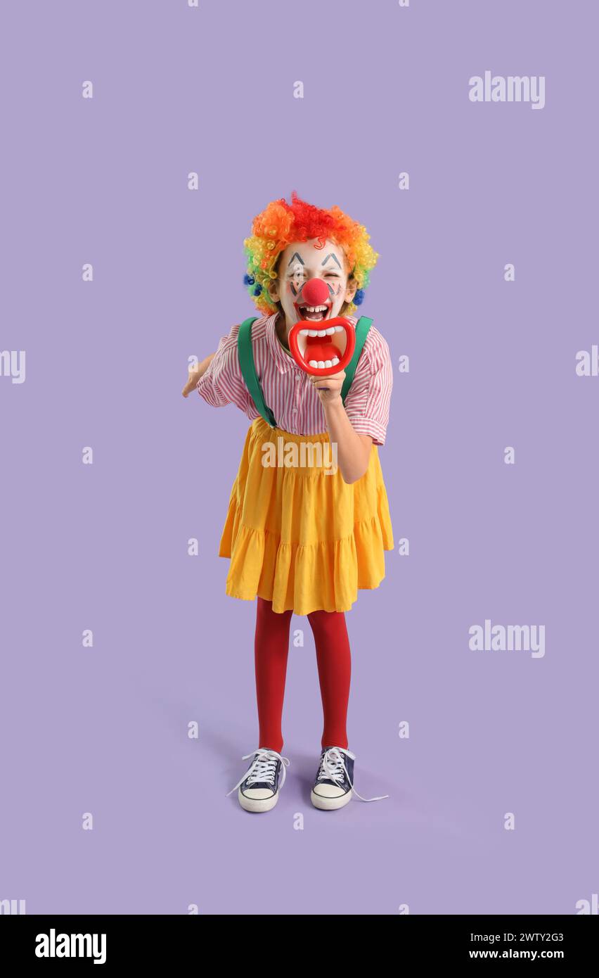 Funny little girl dressed as clown shouting into megaphone on lilac ...
