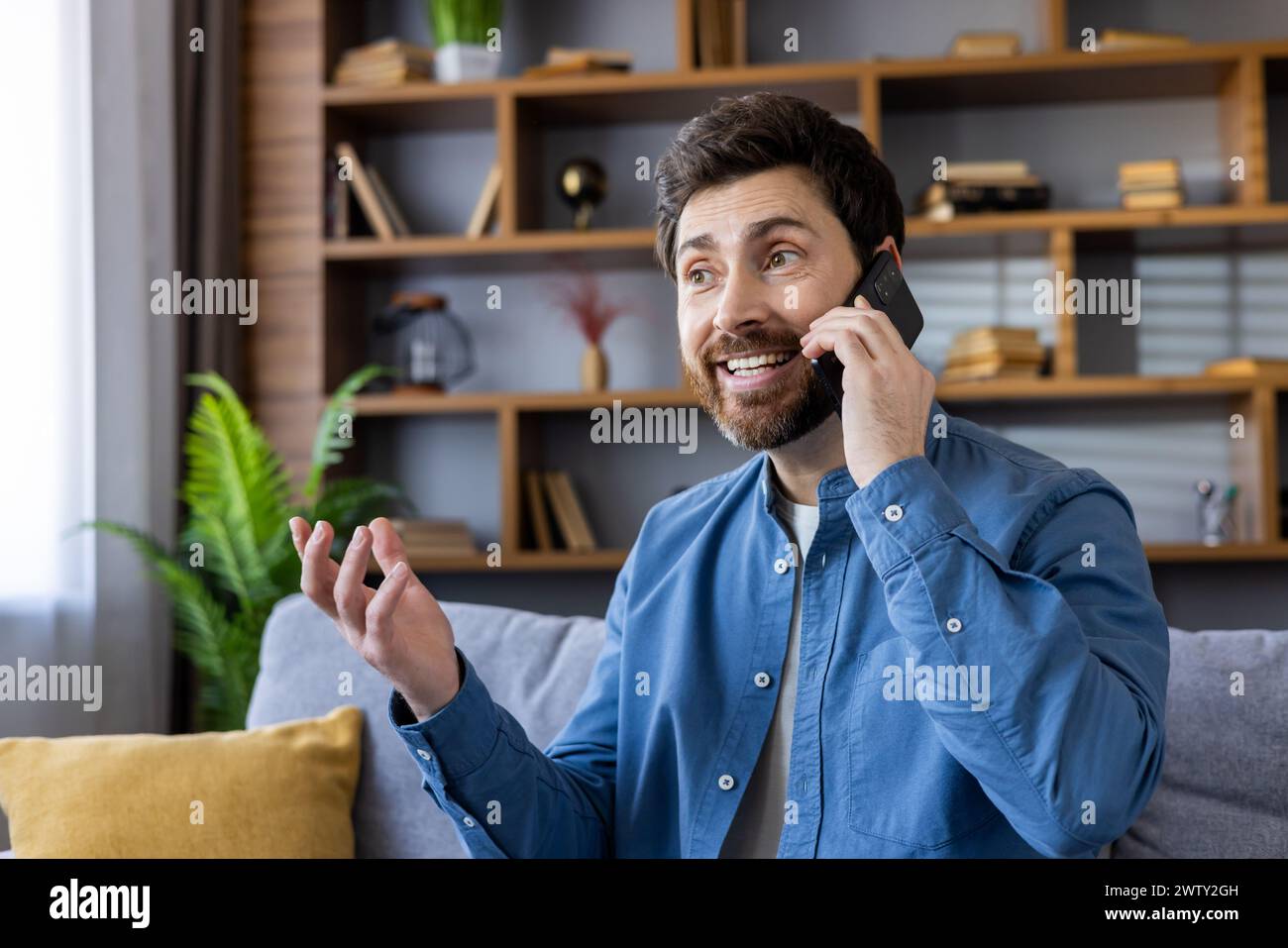 A casually dressed man in a blue shirt gestures as he speaks on a ...