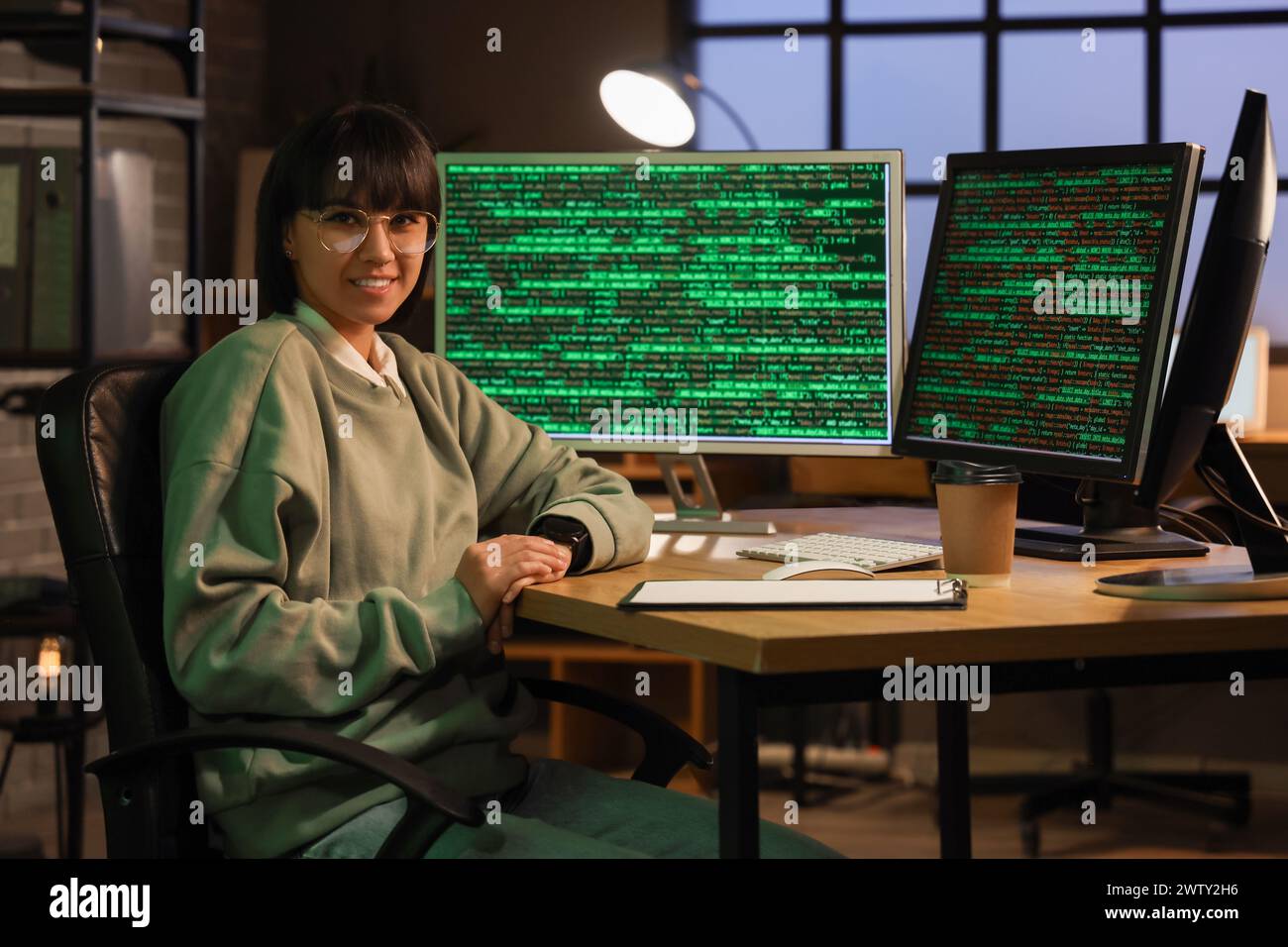 Female programmer working with computer monitors in office at night ...