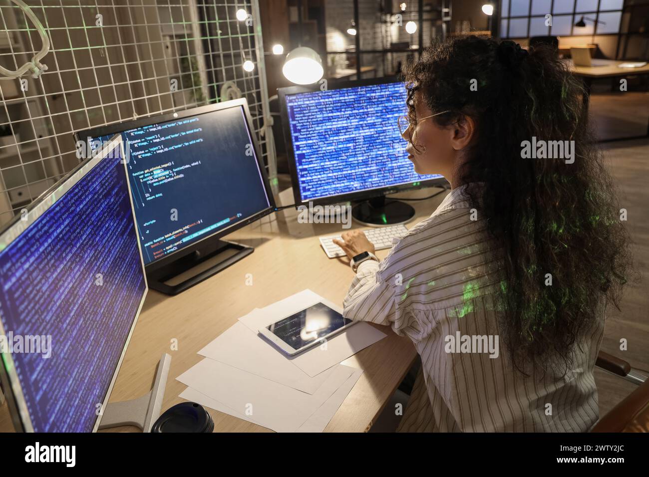 Female African-American programmer with computer monitors working in ...