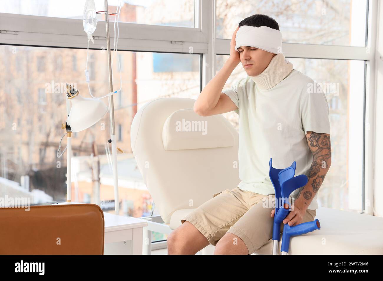 Injured young man after accident with crutches sitting on couch in ...
