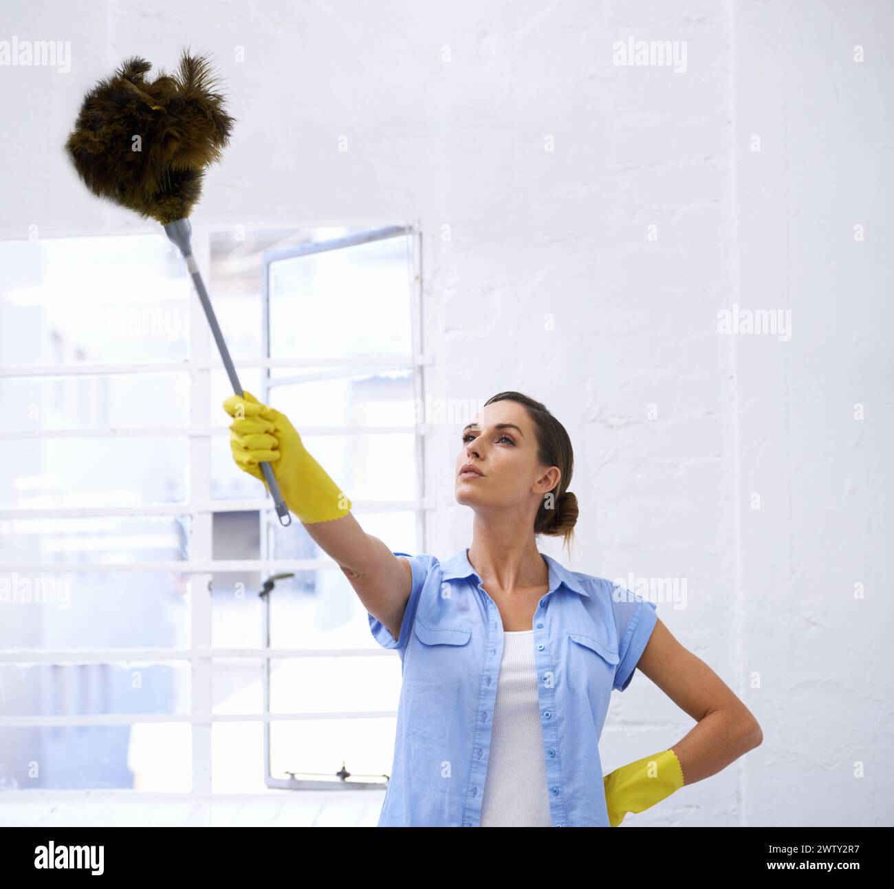 Woman, cleaning and duster for housekeeping in home, feather and worker ...