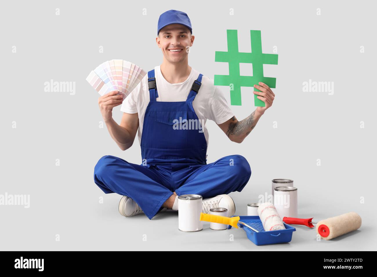 Male painter with palette samples, paint cans and hashtag sign sitting ...