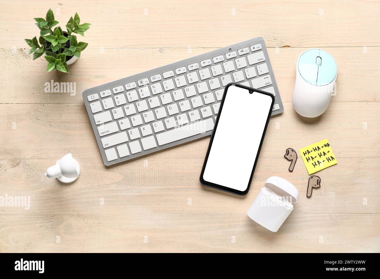 Carton earphones, sticky note, computer keyboard and phone on wooden ...