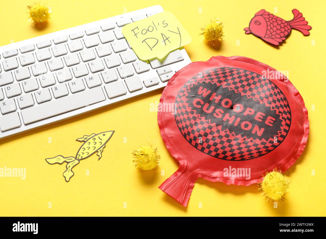 Computer keyboard, sticky note and whoopee cushion on yellow background ...