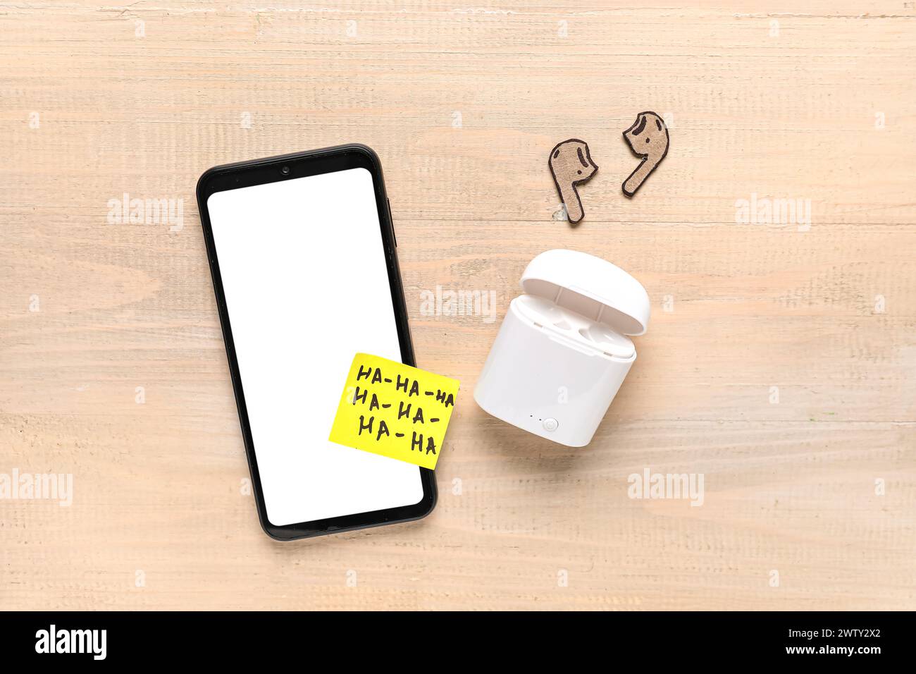 Carton earphones, sticky note and phone on wooden background. April ...