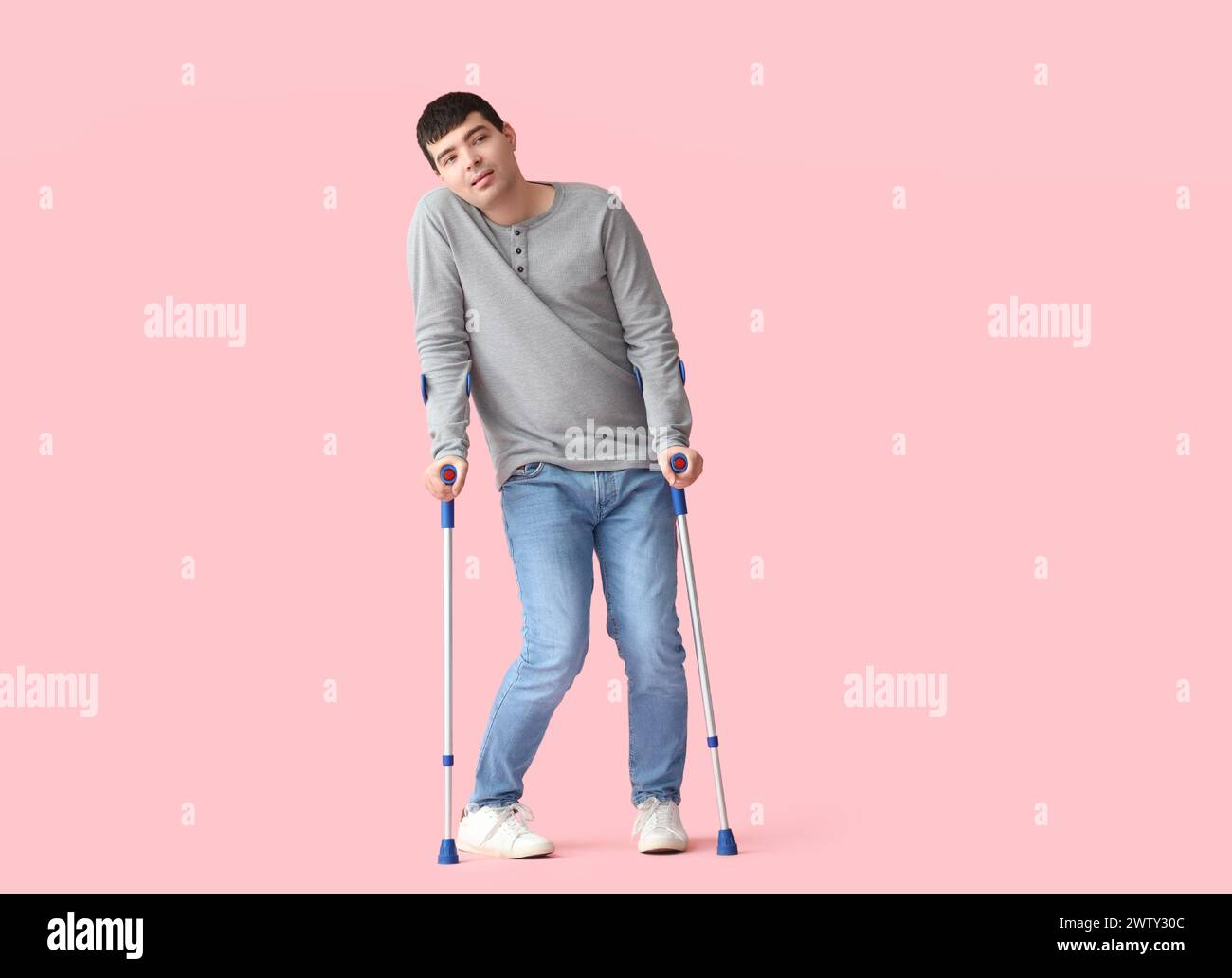 Young man with crutches on pink background. National Cerebral Palsy ...